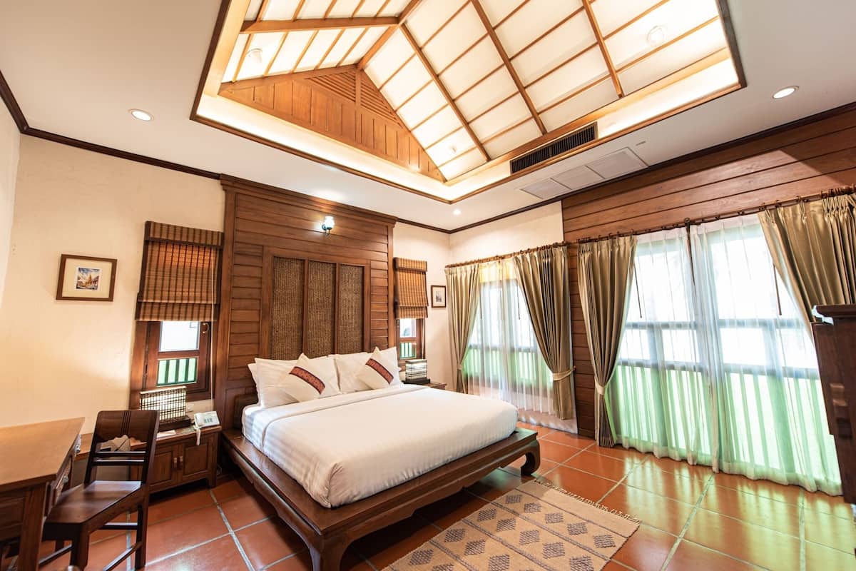 Quarto com cama grande, cabeceira de madeira e claraboia.