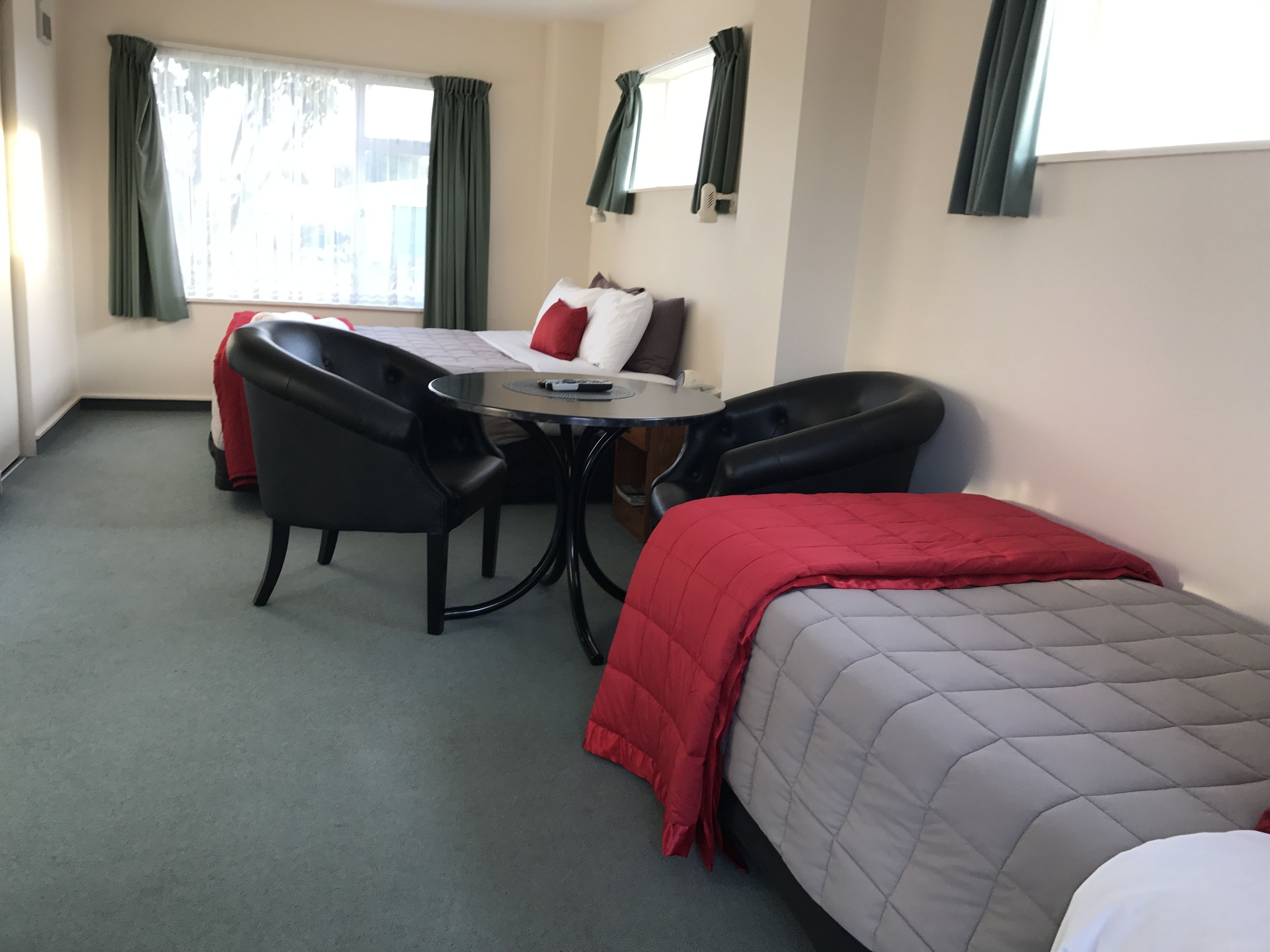Quarto de hotel com uma cama, uma mesa de escritório, duas cadeiras e uma pequena mesa.