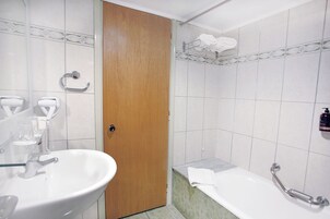 Um banheiro com pia, chuveiro com barra de apoio e porta-toalhas.