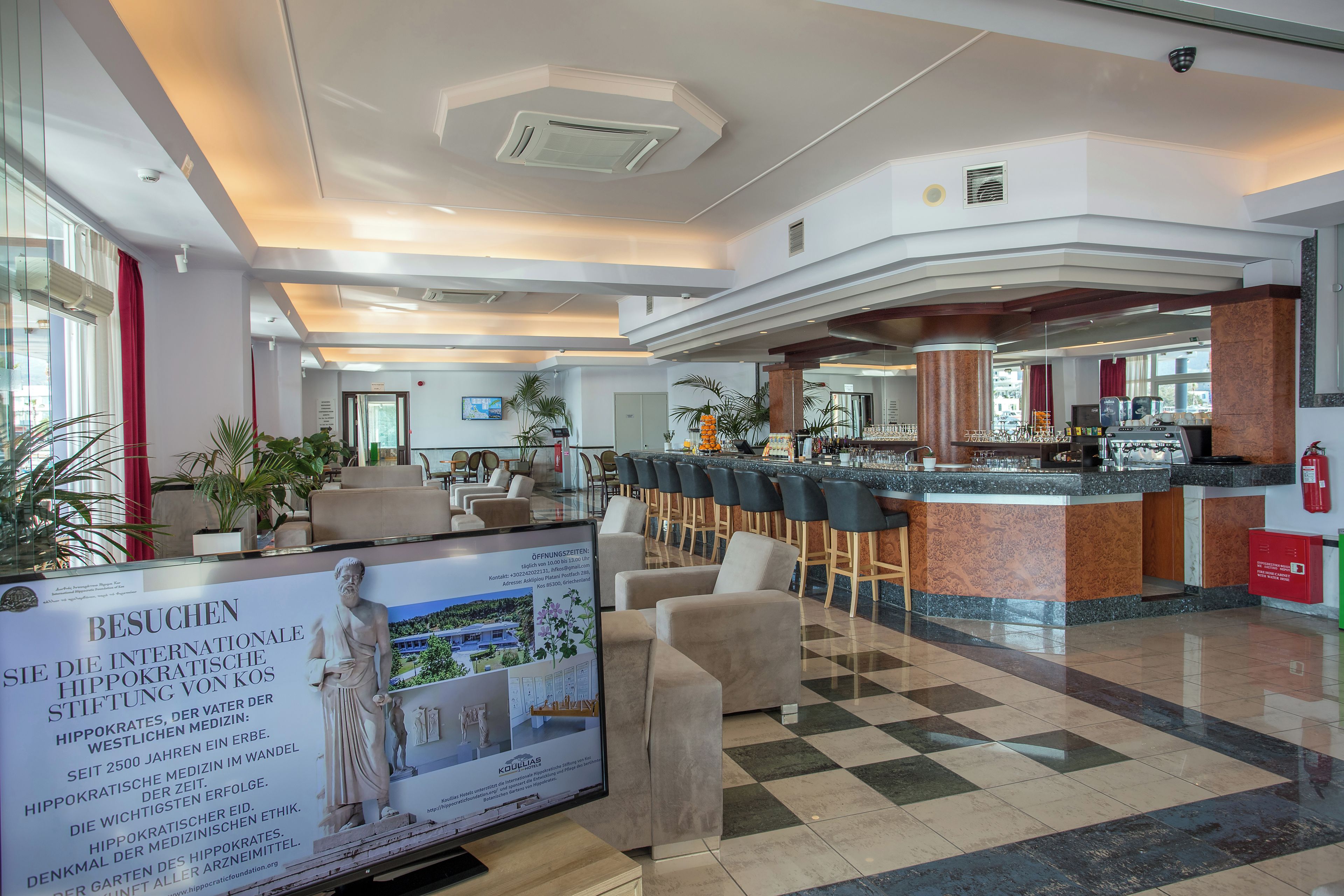 Um saguão de hotel com balcão de recepção, área de estar e bar.