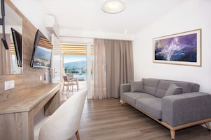 Uma sala de estar moderna com um sofá cinzento, soalho de madeira, uma TV na parede e um quadro.