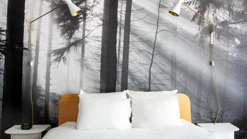 Quarto com uma cama, almofadas brancas e duas mesas de cabeceira.
