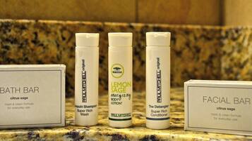 Uma bancada de banheiro com três produtos Paul Mitchell: Bath Bar, Loção Corporal Revitalizante Limão e Sálvia e Condicionador Super Rico The Detangler.