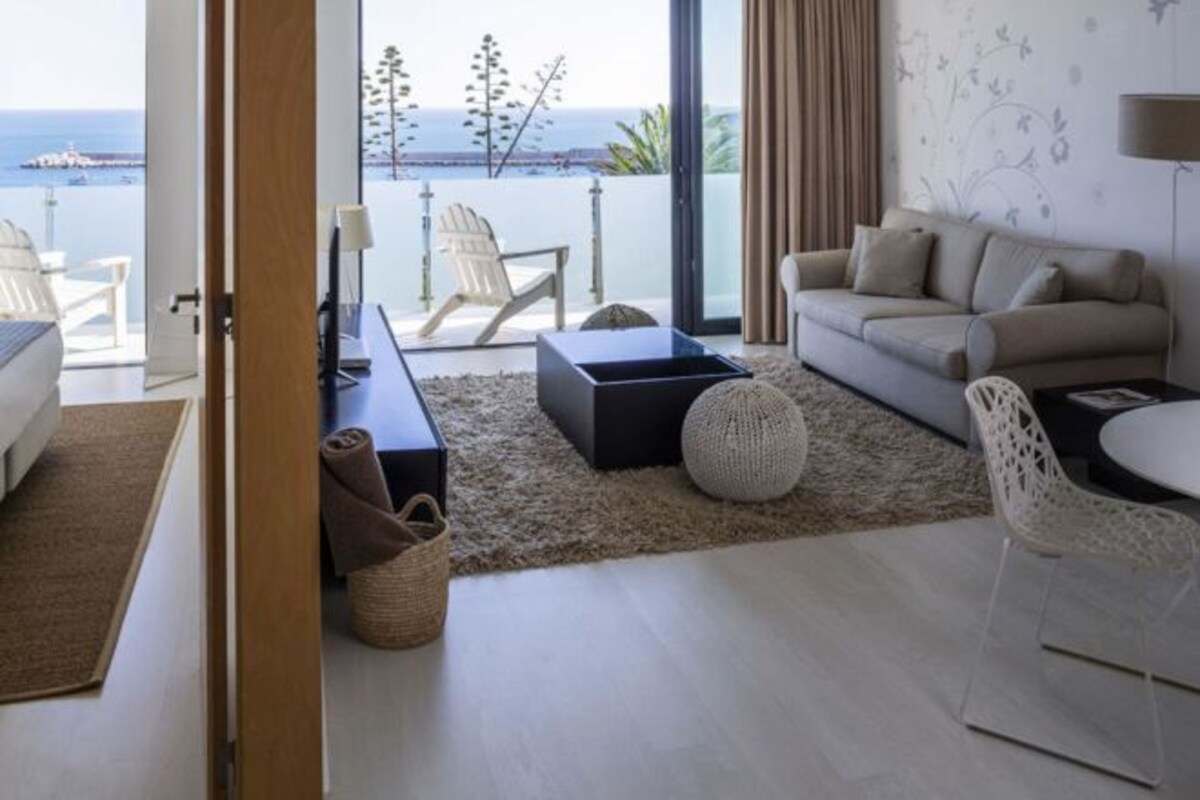 Uma sala de estar moderna com um sofá, mesa de centro e vista para o oceano.