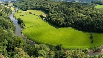 Uma paisagem verdejante com um rio, floresta densa e campos abertos.