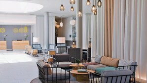 Um hall de hotel moderno com balcão de recepção, área de estar e grandes janelas.