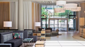Um hall moderno com sofá, poltronas, mesa de centro e balcão de recepção.