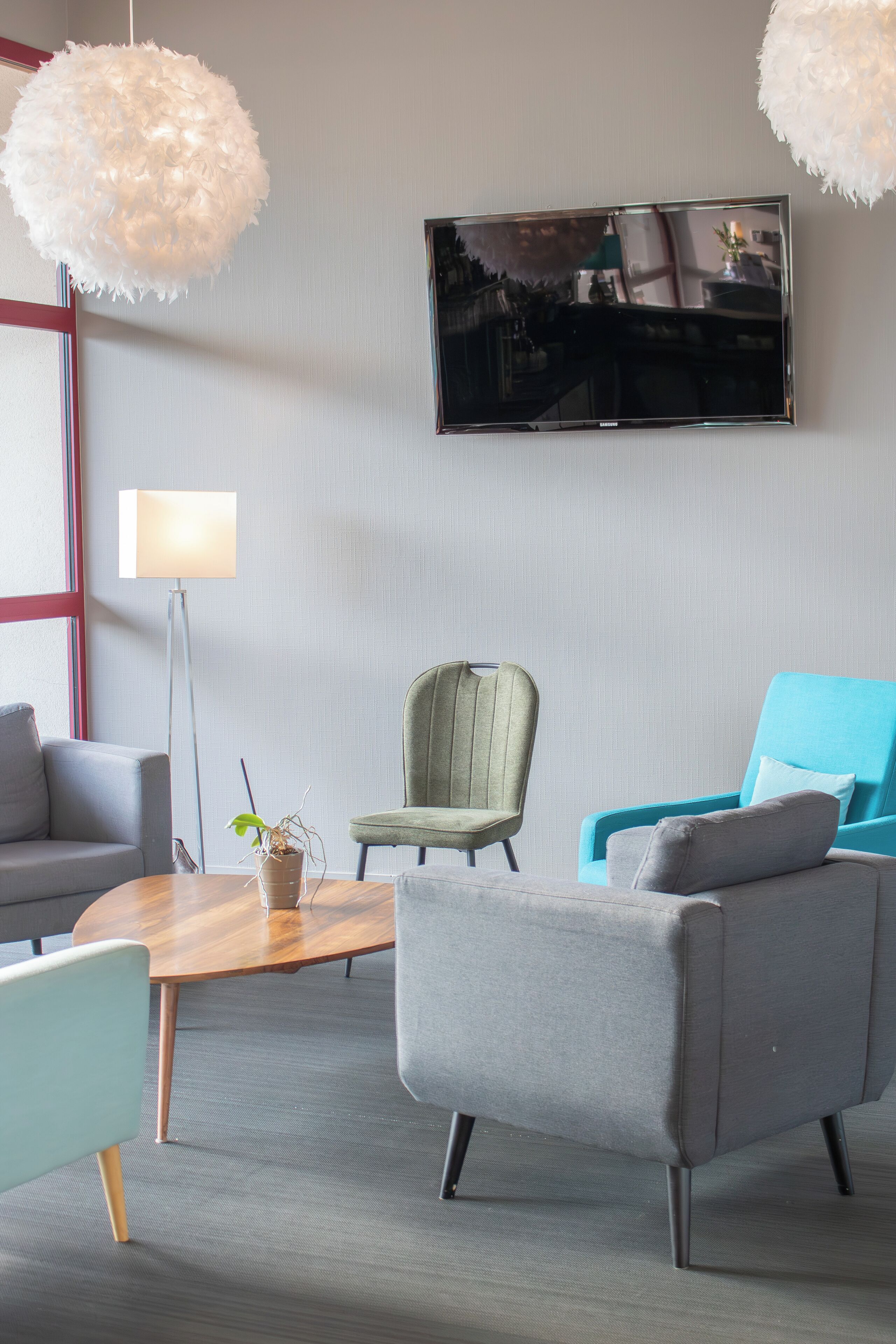Uma sala de estar moderna com uma TV de tela plana na parede, uma mesa de centro redonda de madeira e duas poltronas.