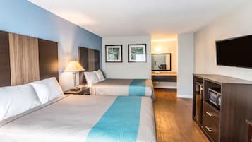 Quarto de hotel com duas camas, televisão, escrivaninha e micro-ondas.
