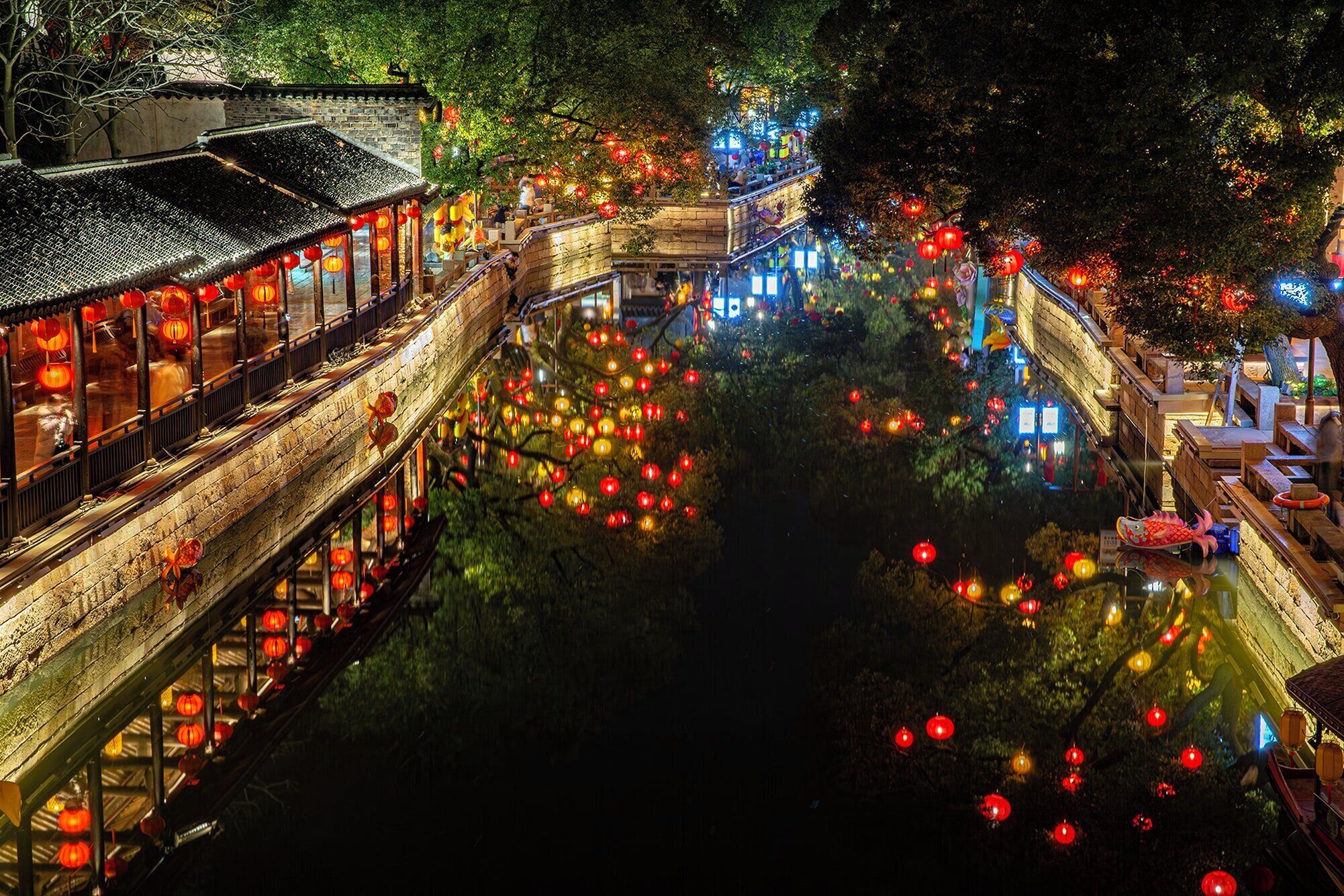 Um pátio tradicional chinês com um canal, pontes de pedra e lanternas.