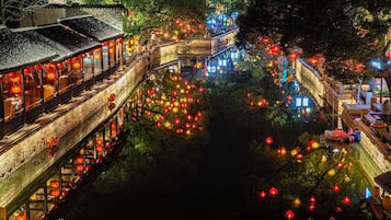 Um pátio tradicional chinês com um canal, pontes de pedra e lanternas.