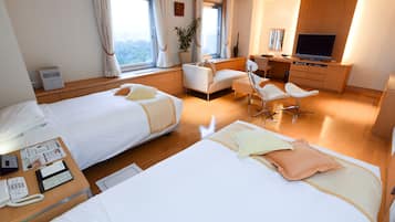 Quarto de hotel com duas camas, uma mesa de escritório com computador, televisão e janela com cortinas.