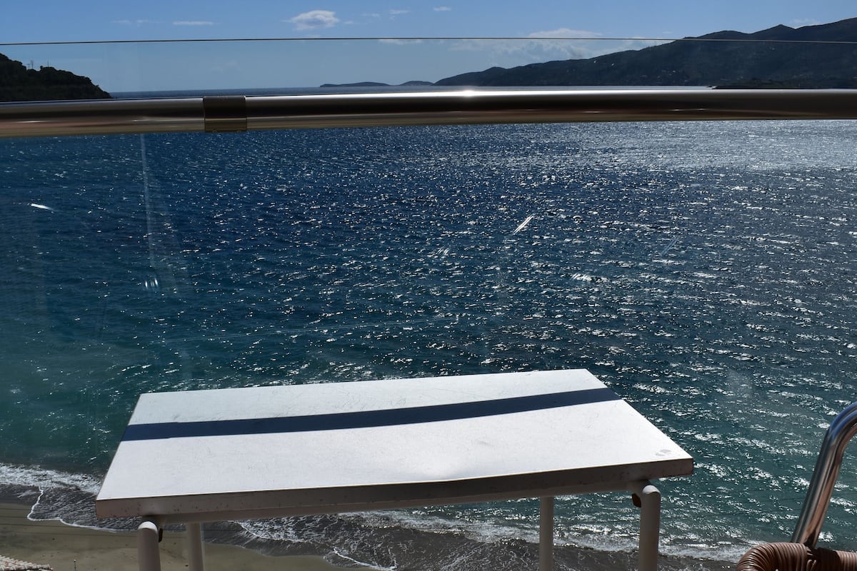 Varanda com mesa e cadeiras dando vista para a praia e oceano.