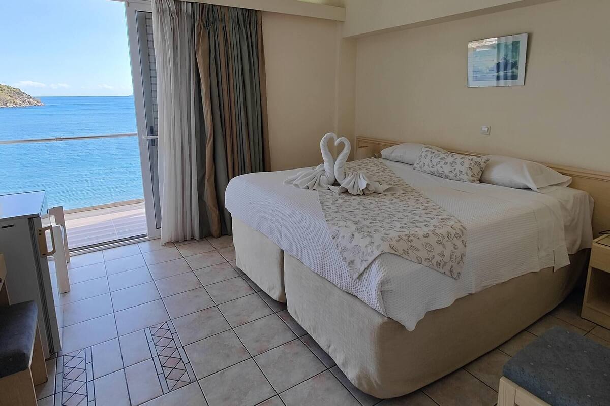 Quarto de hotel com uma cama grande, uma mesa de trabalho e vista para o mar.