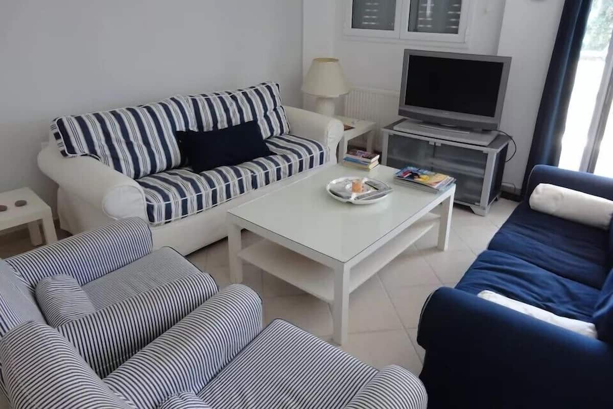 Sala de estar com sofá listrado, mesa de centro, aparador e poltrona azul.