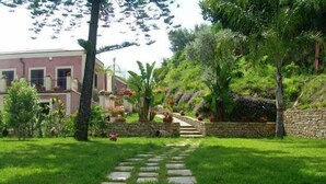 Um caminho que leva a um edifício com parede de pedra e vegetação exuberante.