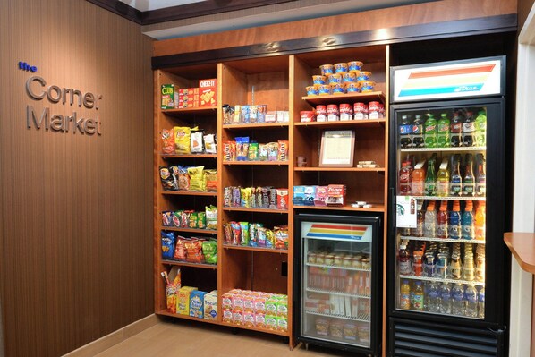 Uma mercearia de esquina com prateleiras repletas de lanches, bebidas e produtos refrigerados.