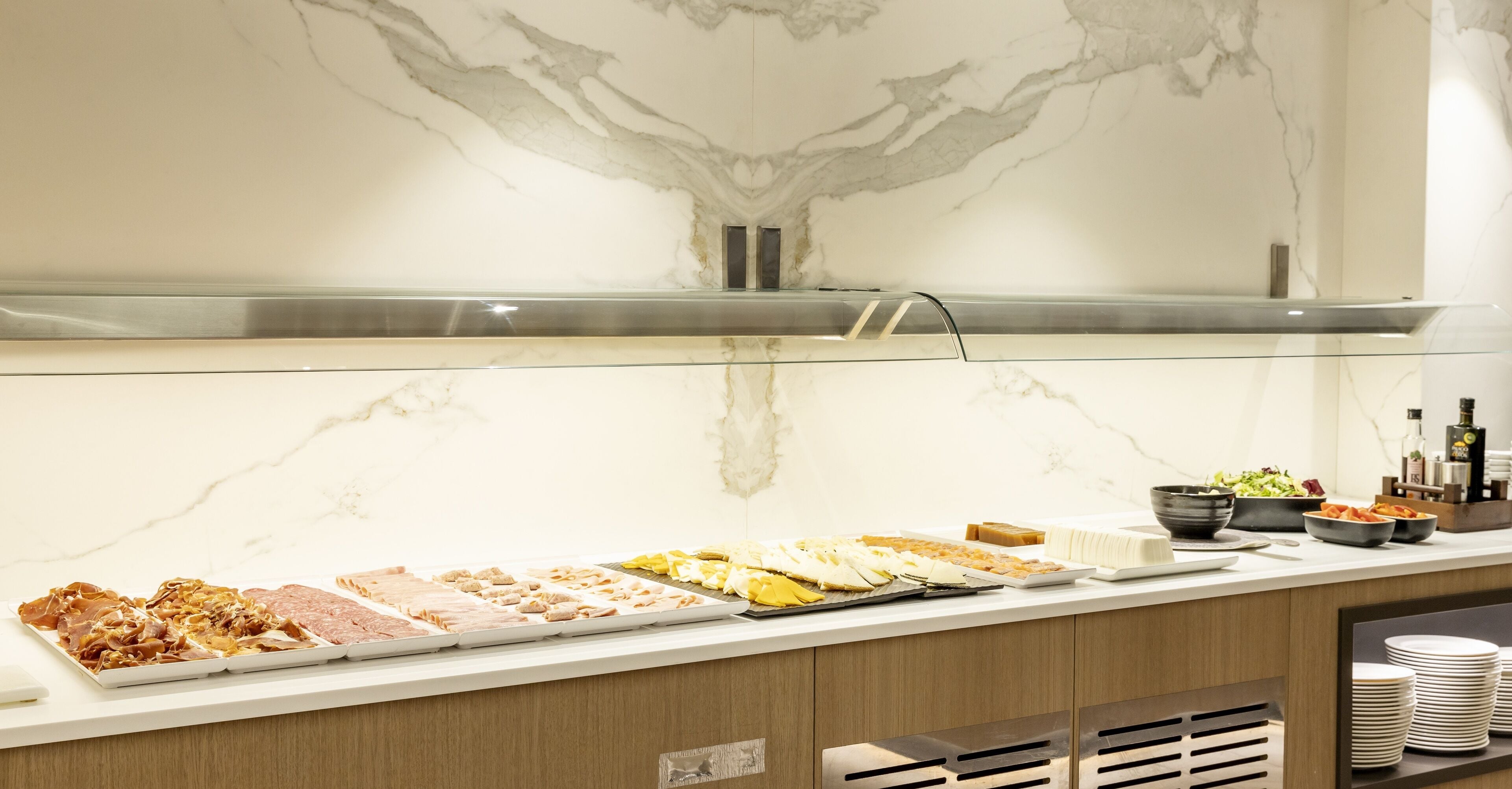 Buffet com diversos alimentos e parede de mármore com um desenho central.