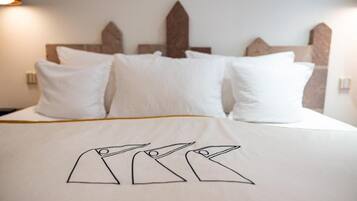 Cama bem arrumada com roupa de cama branca e um desenho geométrico na capa do edredom.
