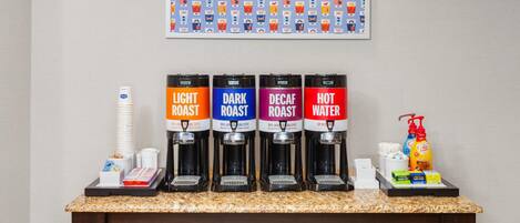 Uma estação de café com quatro dosadores identificados como Café Claro, Café Escuro, Café Descafeinado e Água Quente.