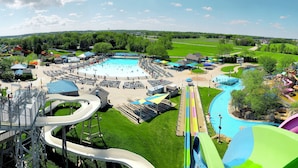Um parque aquático com várias escorregas, uma piscina grande e um campo esportivo ao fundo.