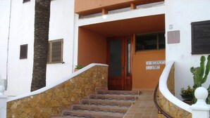 Uma escadaria leva a uma entrada, com uma parede de pedra de um lado e uma parede branca do outro.