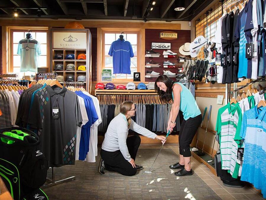 Uma loja de roupas com araras cheias de camisas e chapéus.