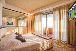 Quarto de hotel com cama, televisão e vista para o exterior.