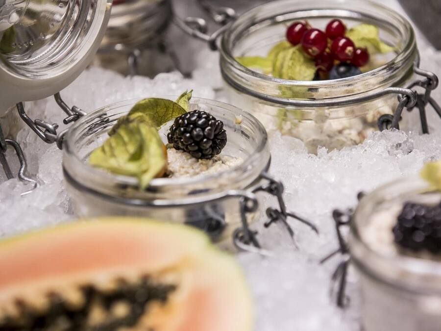 Diversos alimentos sobre gelo, incluindo uma tigela com amoras e outra com frutos vermelhos.