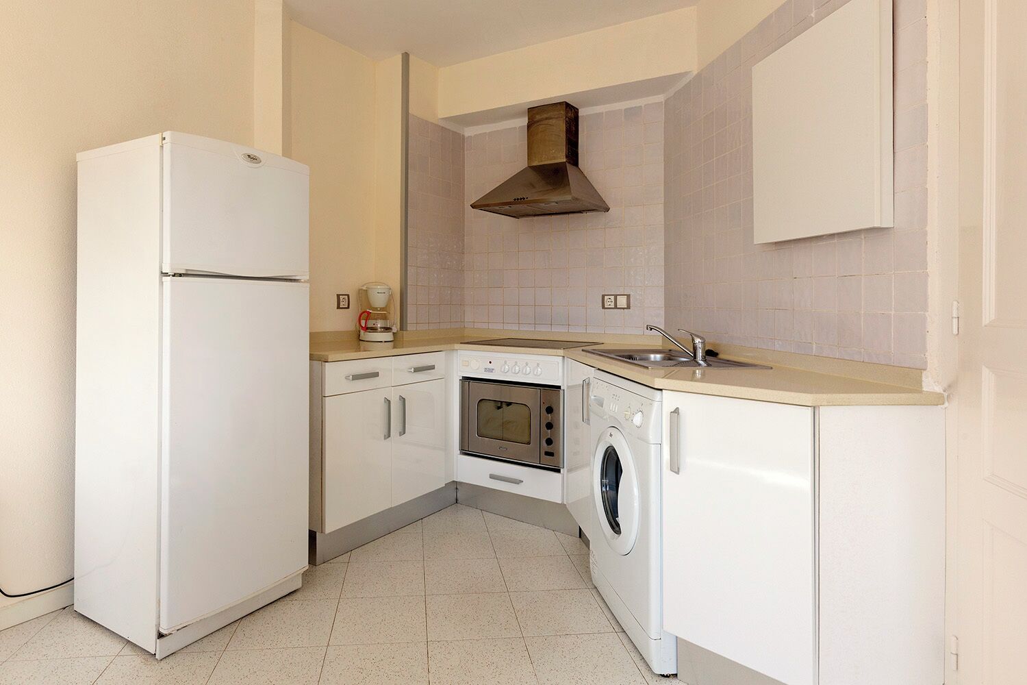Cozinha compacta com geladeira, forno, micro-ondas e máquina de lavar.