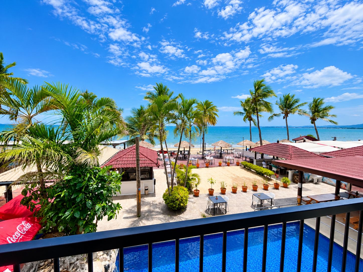 Resort com piscina, área de estar externa e vista para a praia.