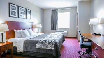 Quarto de hotel com uma cama grande, uma mesa, uma cadeira e uma janela com cortinas.
