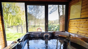 Uma banheira de hidromassagem com vista para um jardim e uma parede de tijolos.