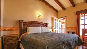 Cama bem arrumada com colcha acolchoada, cabeceira de madeira e mesa de cabeceira com padrão trançado.