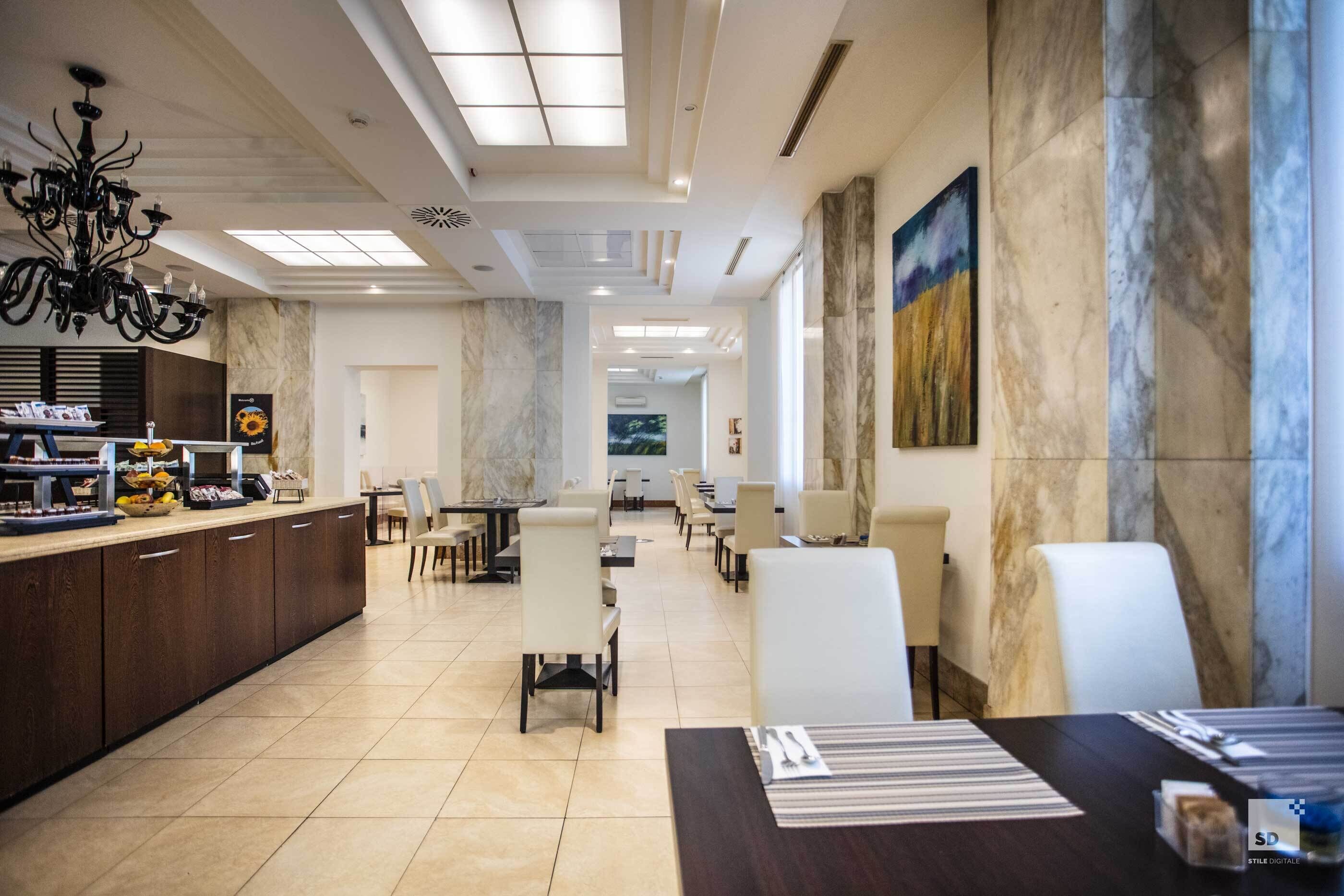 Um amplo hall de hotel com um balcão de recepção extenso, diversas áreas de estar e um candelabro.