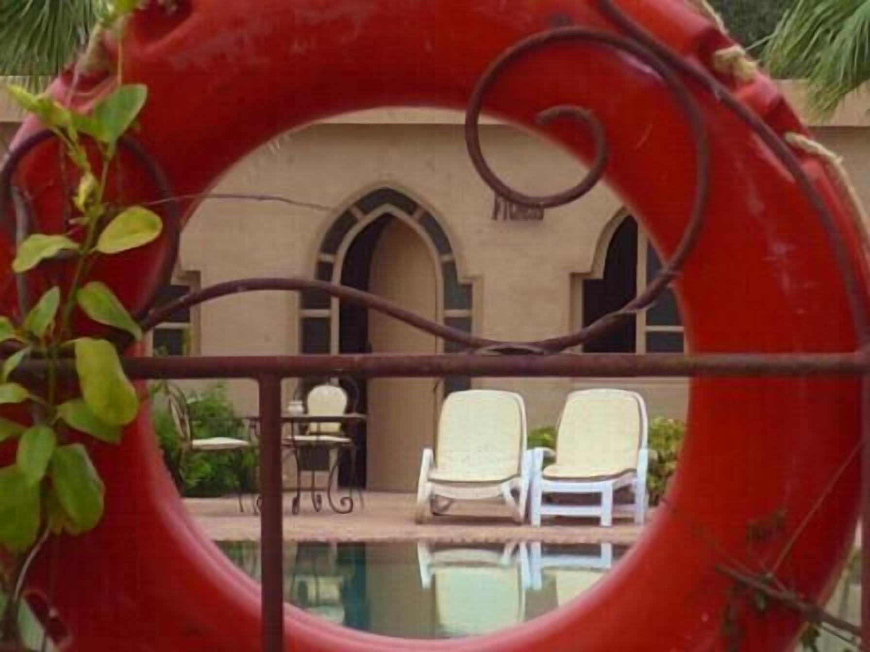 Uma estrutura metálica circular com uma piscina e cadeiras ao fundo.