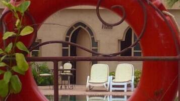 Uma estrutura metálica circular com uma piscina e cadeiras ao fundo.