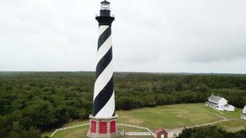 Um farol com design em espiral, cercado por uma grade e um pequeno edifício.