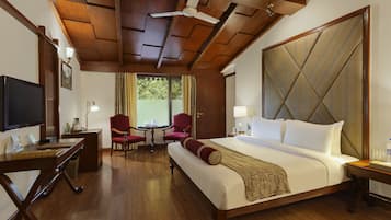 Quarto de hotel com uma cama grande, teto de madeira, televisão, escrivaninha e uma cadeira.