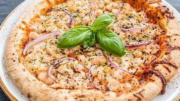 Pizza com cobertura e folhas de manjericão em um prato.