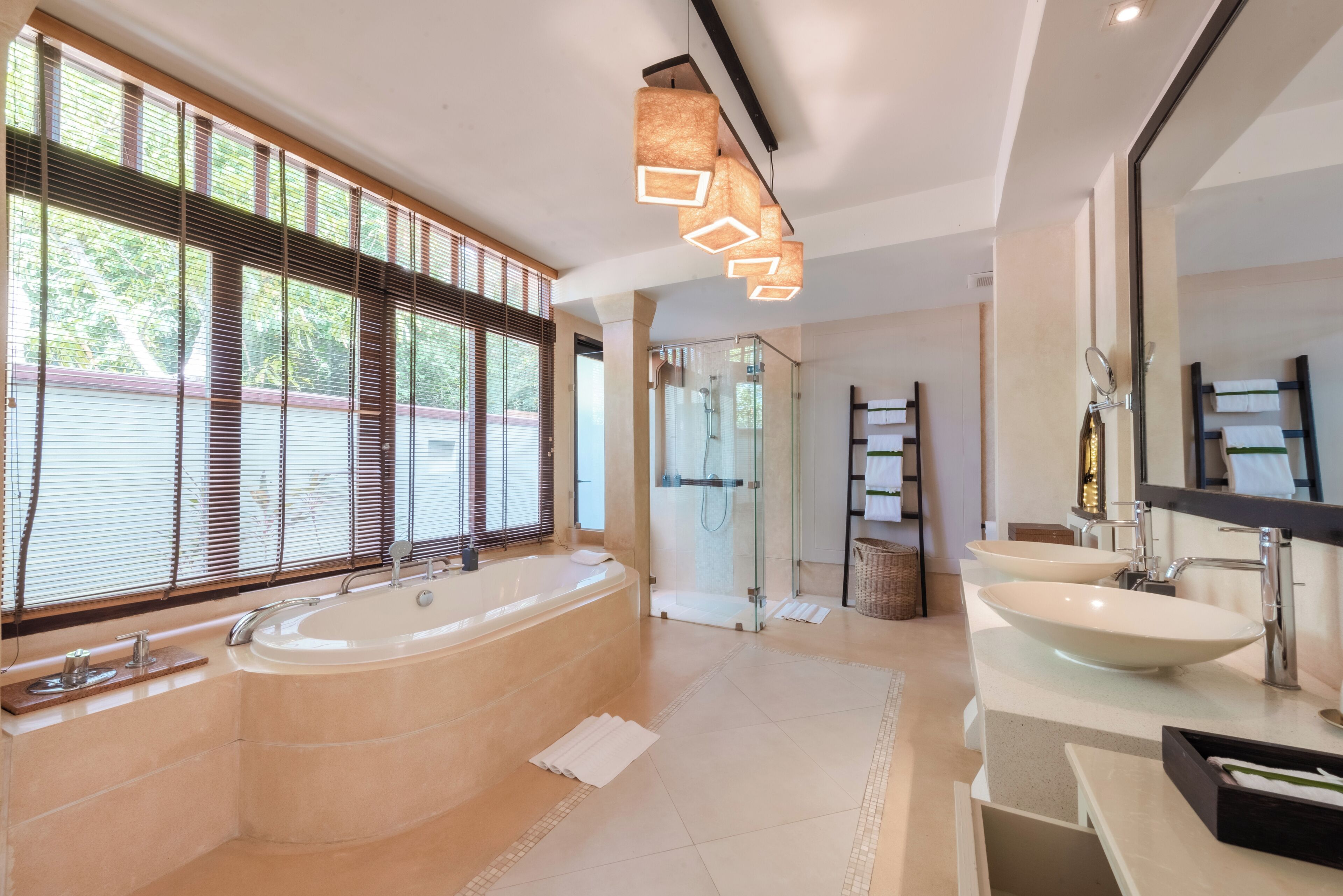 Uma casa de banho moderna com uma banheira grande, duas pias e um chuveiro com parede de vidro.