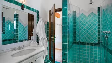 Casa de banho com um espelho grande, uma pia e um chuveiro com azulejos verdes.