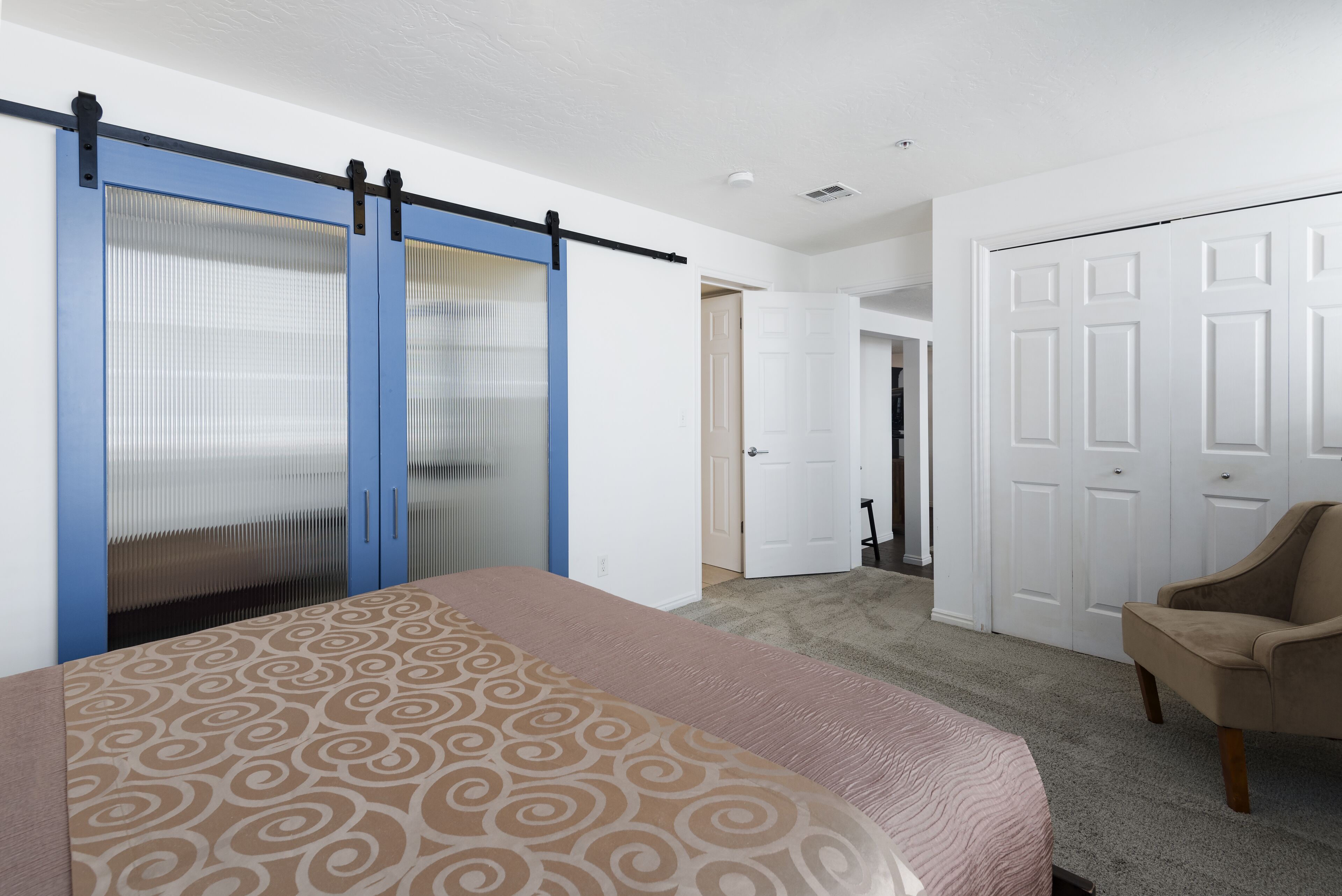 Quarto com cama, cadeira, porta deslizante e armário.
