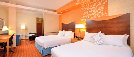 Quarto de hotel com duas camas, uma escrivaninha e uma cadeira.