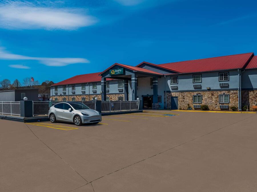 Um hotel com telhado vermelho, fachada de pedra e uma placa com a inscrição "Quality Inn".