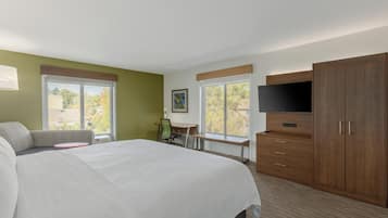 Quarto de hotel com uma cama grande, uma escrivaninha com cadeira, televisão e guarda-roupa.