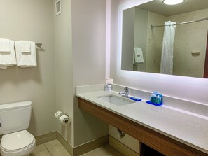 Uma casa de banho com sanita branca, lavatório com espelho em cima e um porta-toalhas com duas toalhas.