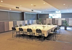 Uma sala de conferências com uma mesa comprida, várias cadeiras e garrafas de água sobre a mesa.