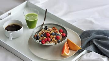 Uma bandeja de café da manhã com uma tigela de cereal, uma xícara de café, um copo de suco verde e duas metades de uma toranja.