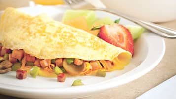 Prato de pequeno-almoço com omelete, legumes e um copo de sumo de laranja.